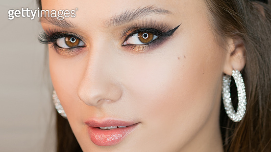 Portrait of a young beautiful brunette woman with bright eye makeup ...