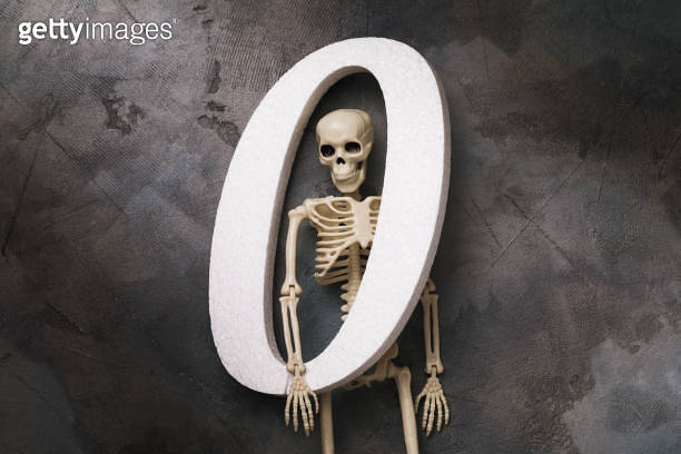 Human skeleton and number zero on a dark background, top view. Zeroing ...