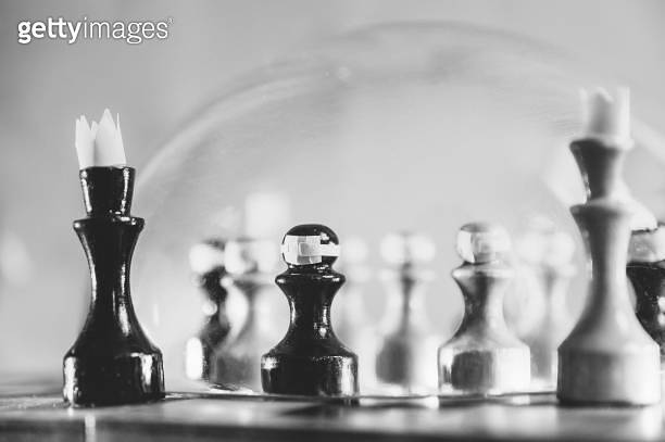 A masked chess pawn under a dome of isolation opposite the figure of ...