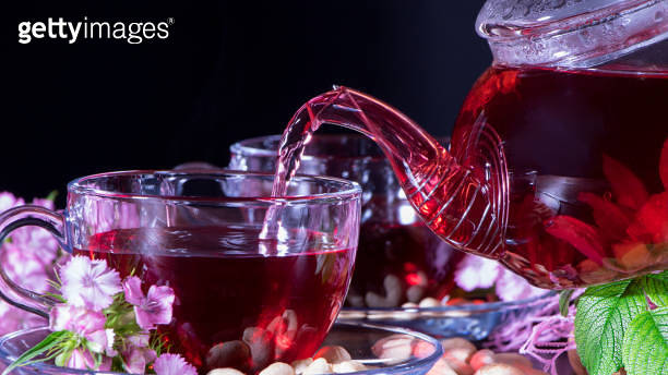 Red tea, hibiscus, karkade, Rooibos. A woman pours tea into a Cup ...