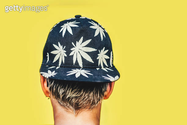 Girl in sunglasses and cap with leaves of marijuana smokes on yellow ...