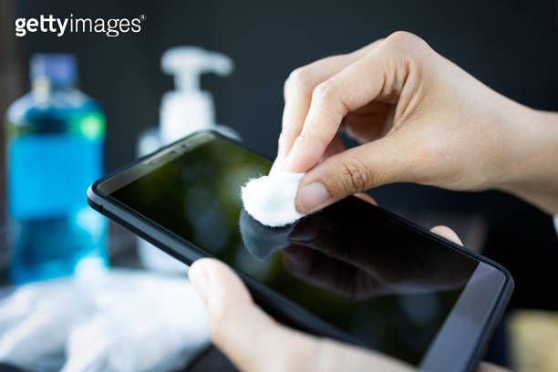 Hands of girl using cotton wool with alcohol to wipe on mobile phone to ...