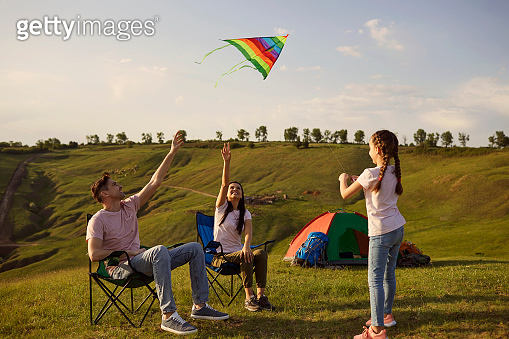 Happy family tourist on a campsite have fun playing with a kite on ...