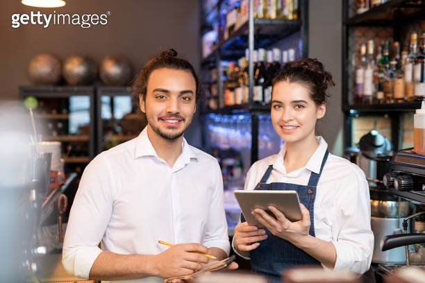 Two young smiling service staff representatives standing in front of ...