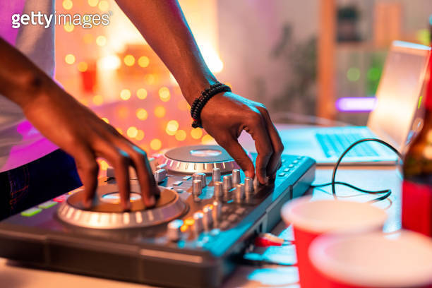 Hands of African guy moving turntable and turning switch while mixing ...