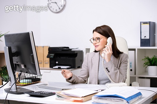 Pretty young secretary working by desk in front of computer monitor 이미지 ...