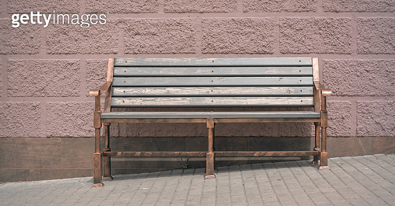 lonely wooden bench with metal wrought railing and empty seat stands on ...