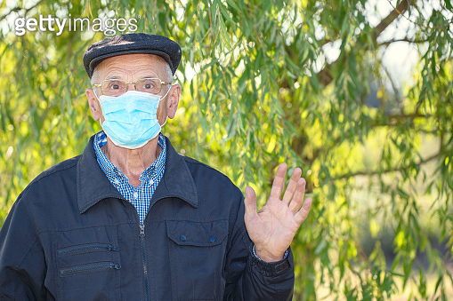 aged old vulnerable man with wave gesture wearing cap glasses and ...
