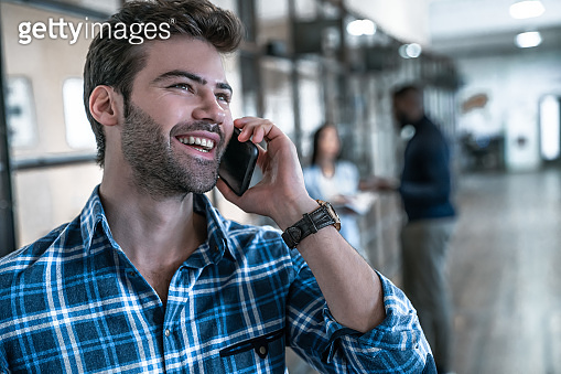 Quick business talk. Handsome young smiling man talking on the phone ...