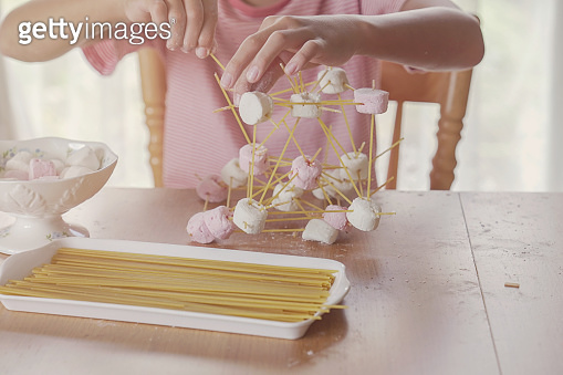 child building tower with spaghetti and marshmallow learning remotely ...