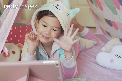 Mixed race Asian girl making facetime video calling with tablet at home ...