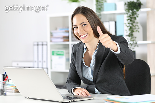 Happy executive with thumbs up looking camera at office (1251322024 ...