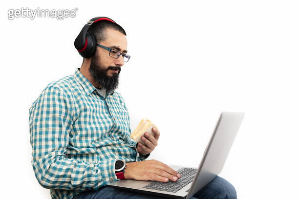 man typing on a laptop while eating a sandwich 이미지 (1253390918) - 게티이미지뱅크