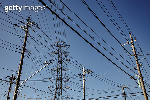 Electrical wiring and power poles crossing through a high voltage pylon ...