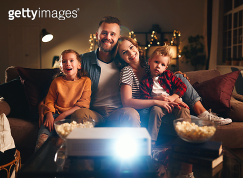 family mother father and children watching projector, TV, movies with ...