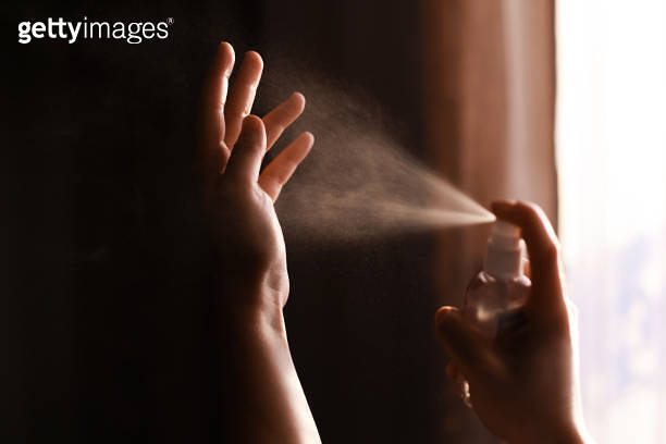 Disinfecting hands. Person using antiseptic spray on hands for ...