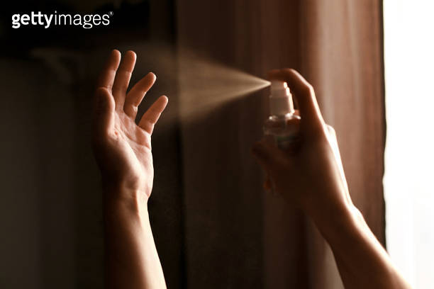 Disinfecting hands. Person using antiseptic spray on hands to prevent ...