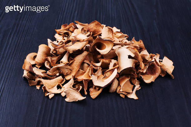 Edible dried mushrooms pile black wooden background close up, dry ...