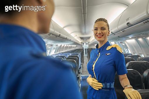 Cheerful airline hostess smiling to her colleague in the plane 이미지 ...