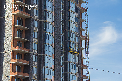 Facade work with construction cradle. Wall decoration of a building ...
