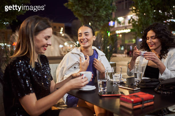 Carefree young women having fun enjoying coffee at a cafe at night 이미지 ...