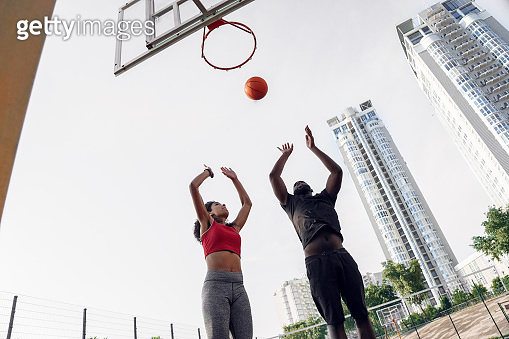 Outdoors Activity. African couple on basketball court guy throwing ball ...