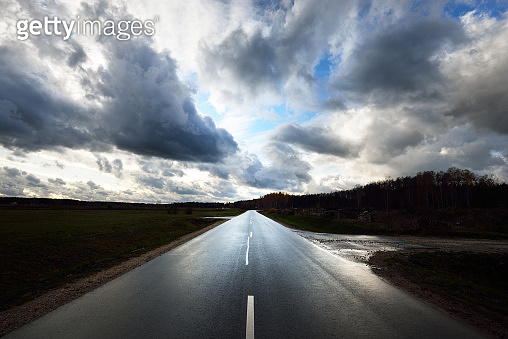 Storm clouds above the empty asphalt road. Agricultural fields and ...