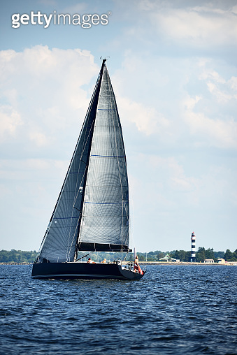 Sloop rigged yacht sailing in on a clear day. Close-up view of the mast ...