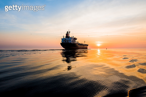 Large cargo ship at sunset. Evening clouds and bright sunlight. Baltic ...