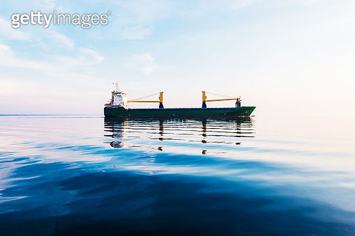 Large cargo crane ship at sunset. Evening clouds and bright sunlight ...
