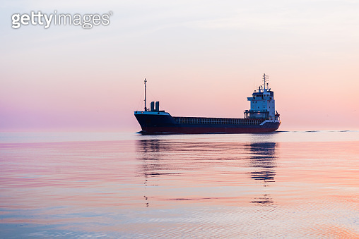 Large cargo ship at sunset. Colorful evening clouds and bright sunlight ...
