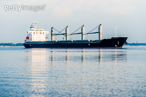 Large cargo crane ship at sunset. Evening clouds and bright sunlight ...
