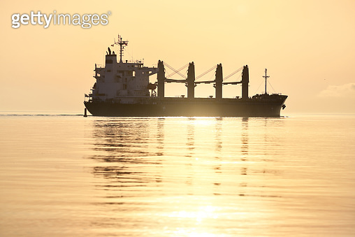 Large cargo crane ship at sunset. Evening clouds and bright sunlight ...