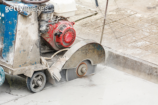 Worker using diamond saw blade machine cutting concrete road at ...