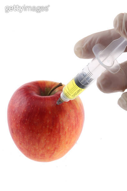 Injection into an apple. A hand in a medical glove with a syringe on a ...