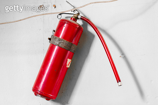 A red balloon fire extinguisher hangs on a white wall. Fire safety in ...