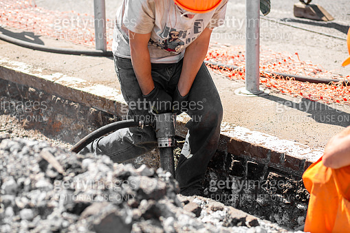 Repair work on the city street. Professional workers dismantle part of ...