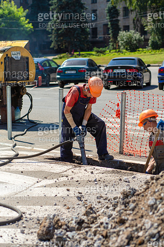 Repair work on the city street. Professional workers dismantle part of ...