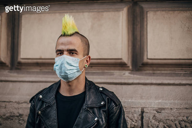 Portrait of a punker with protective face mask standing outdoors by the ...