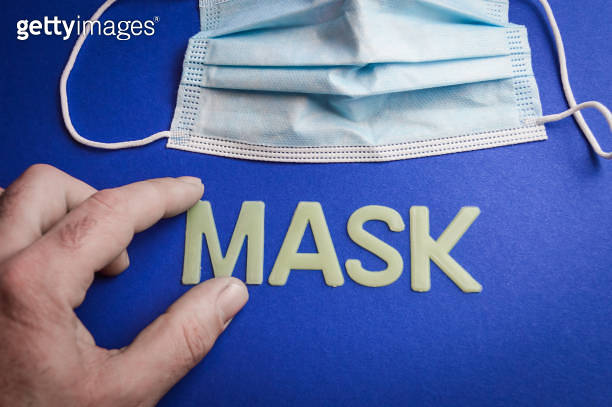 Human hand holding the word Mask written with plastic letters on blue ...
