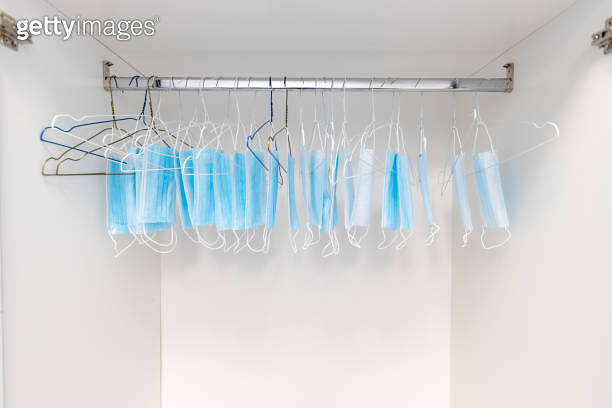 Disposable surgical masks hanging on hangers in a wardrobe closet ...