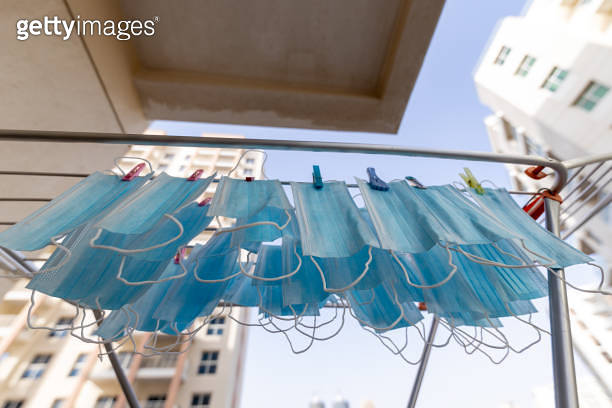 Blue disposable surgical mask washed and hanging on a drying rack ...