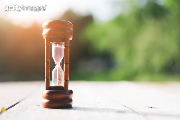 Small hourglass show time is flowing on sand beach texture background ...