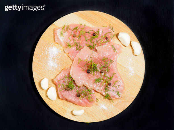 Sliced pieces of meat turkey filet, garlic, salt, fennel on black ...