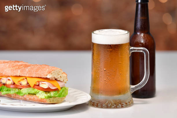 view of a mug of beer next to a delicious looking sub sandwich with ...