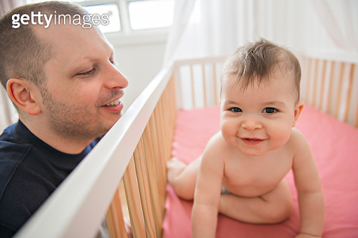 father look infant daughter into baby crib 이미지 (1213708835) - 게티이미지뱅크