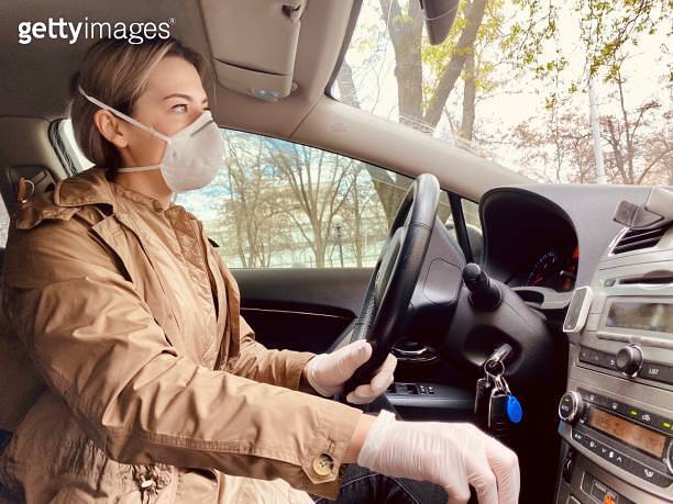 girl in a flu protective mask and gloves, against coronavirus, driving ...