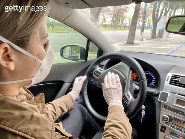 girl in a flu protective mask and gloves, against coronavirus, driving ...