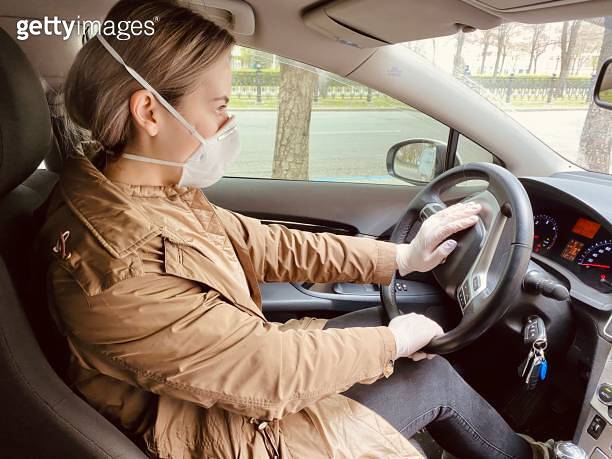 girl in a flu protective mask and gloves, against coronavirus, driving ...