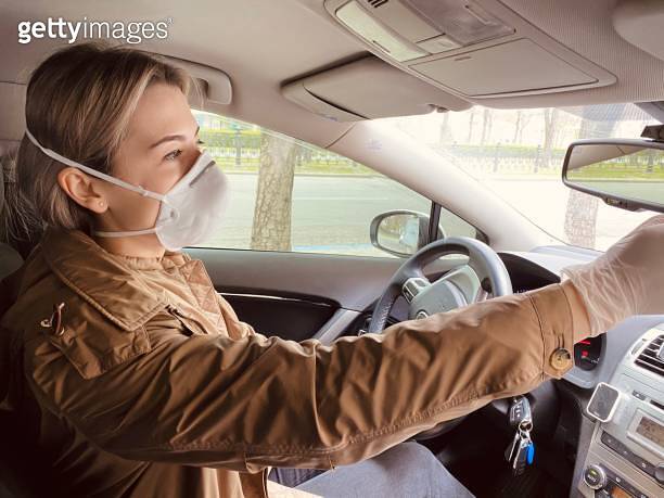 girl in a flu protective mask and gloves, against coronavirus, driving ...